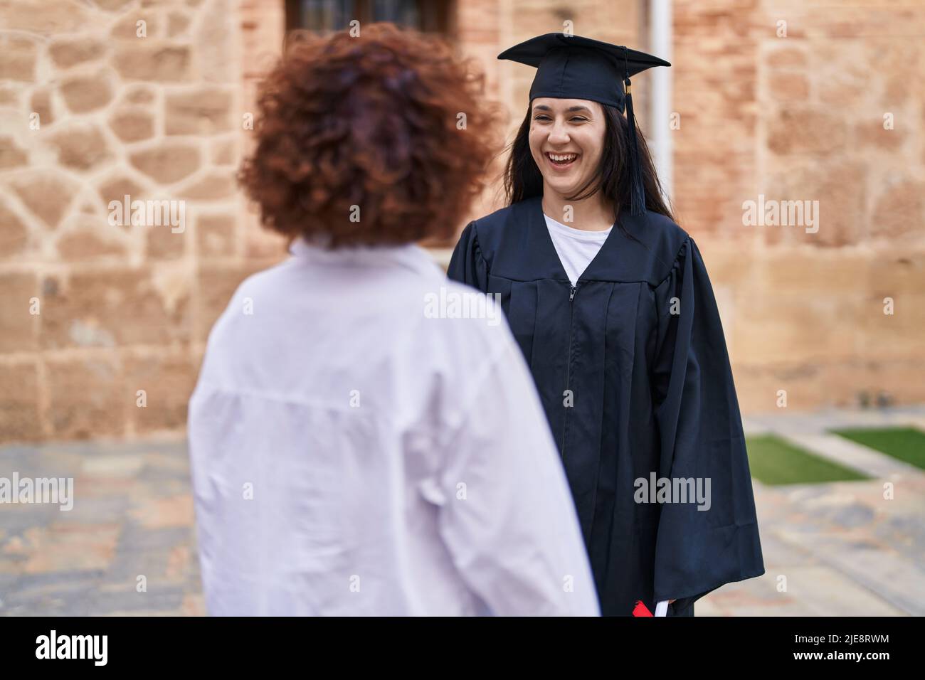 Two women mother and daughter celebrating graduation at campus ...