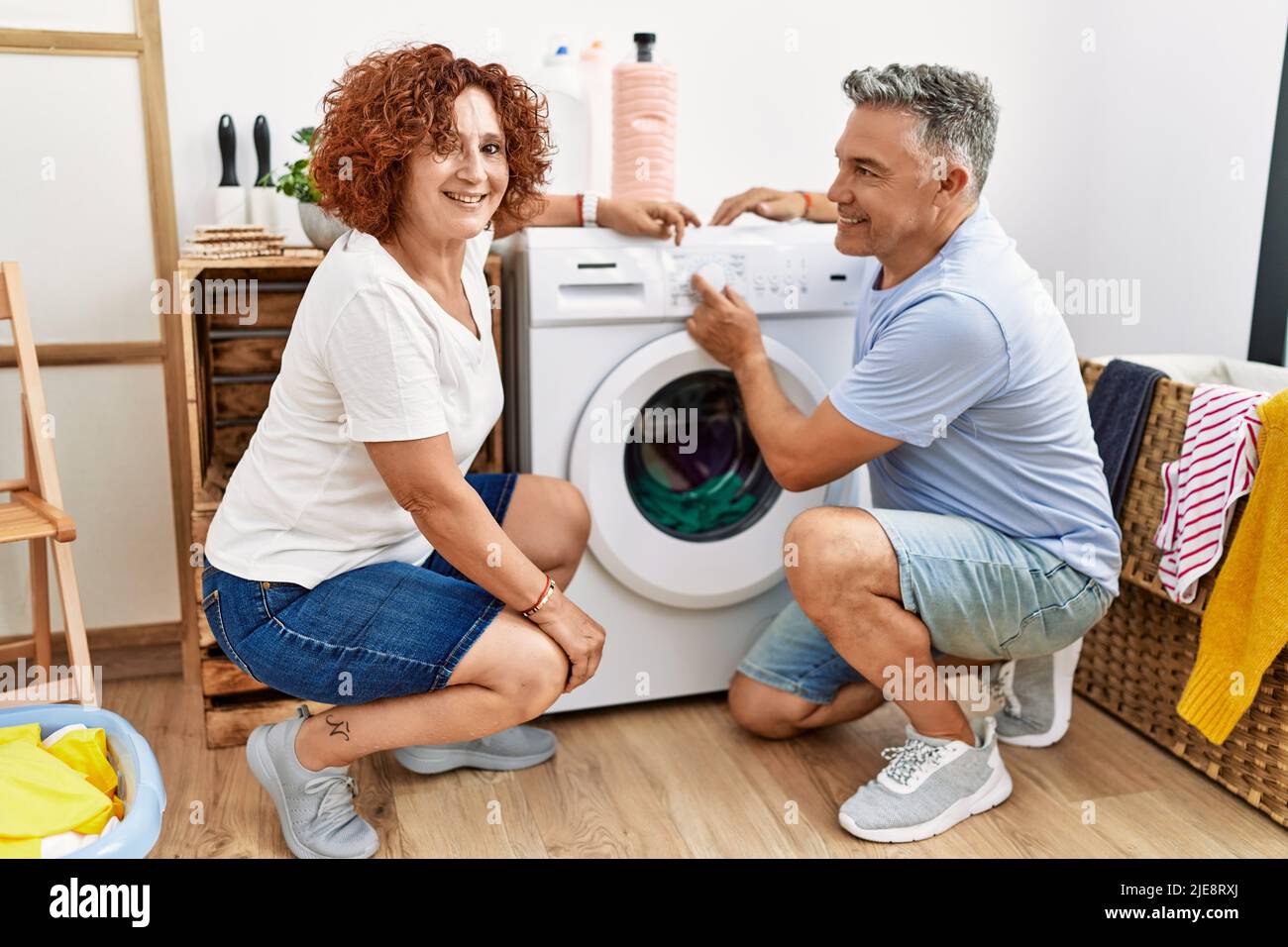 Middle age man and woman couple smiling confident turning on washing clothes at laundry Stock ...