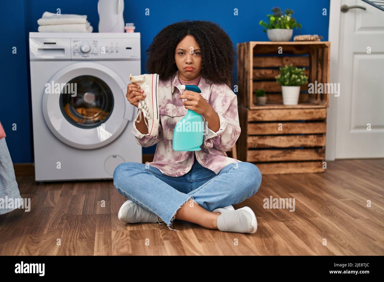 Young african american woman cleaning shoes at laundry room depressed ...