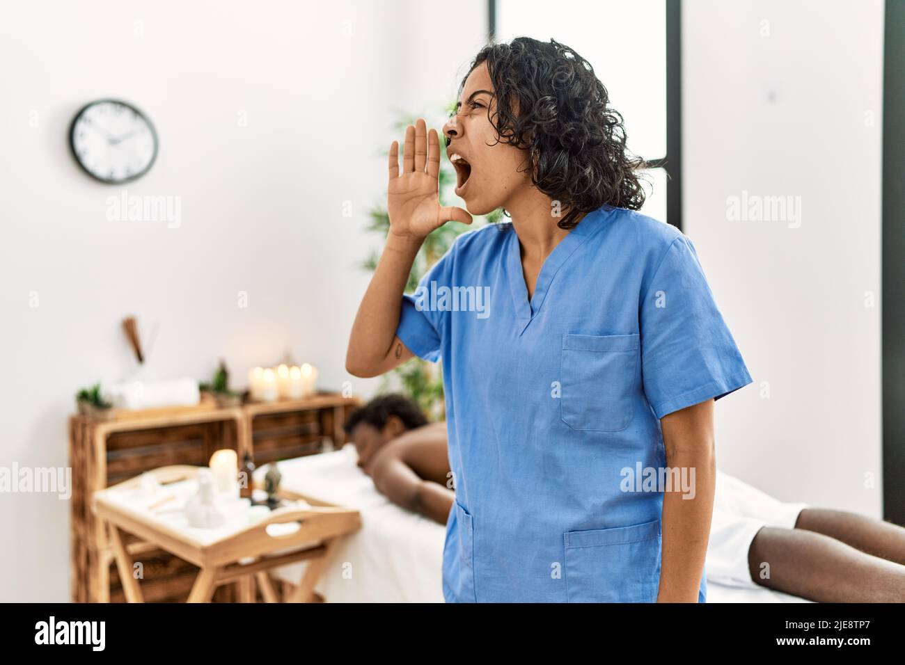 Young therapist woman at wellness spa center shouting and screaming ...