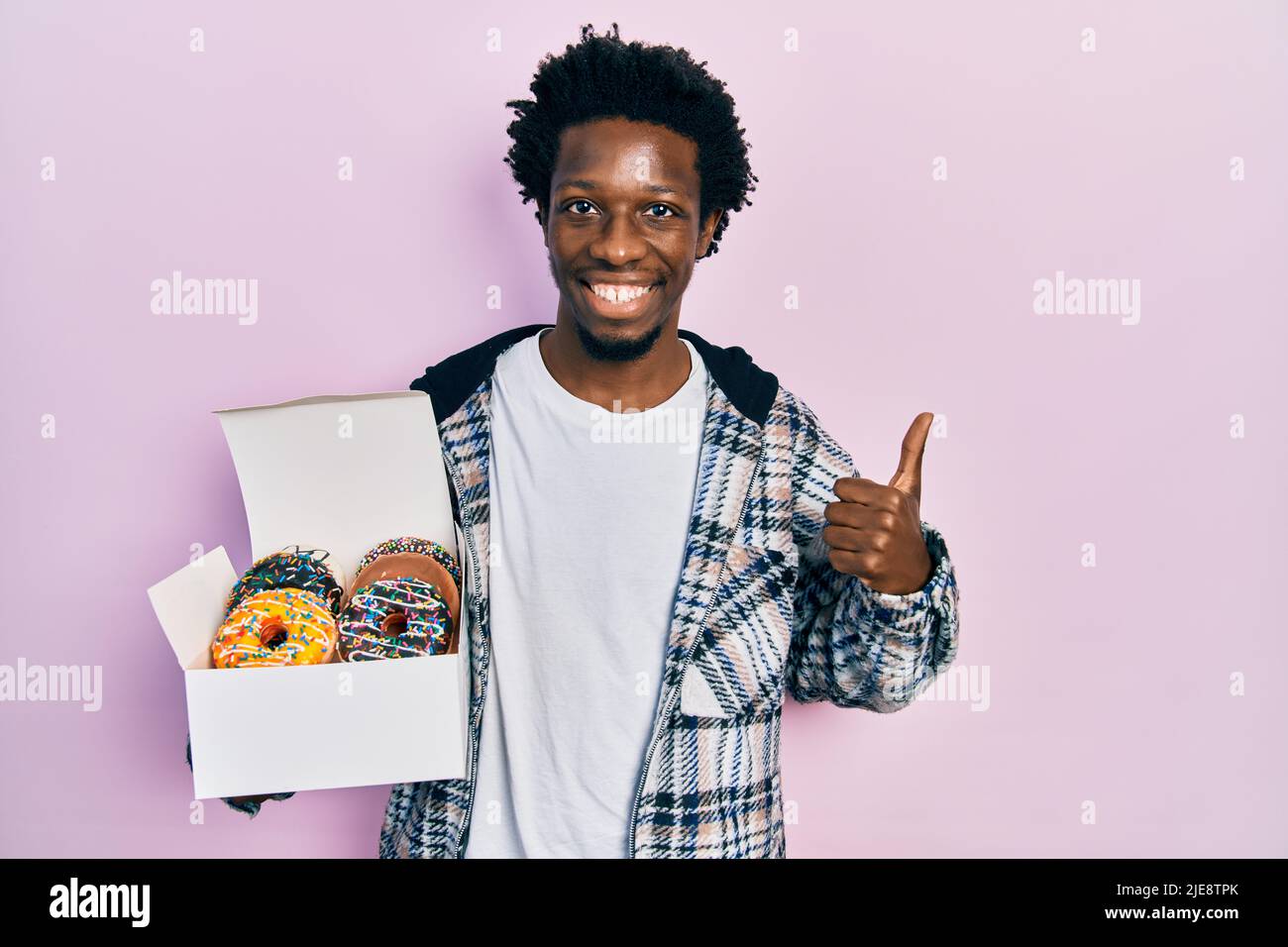 Young african american man holding tasty colorful doughnuts box smiling ...