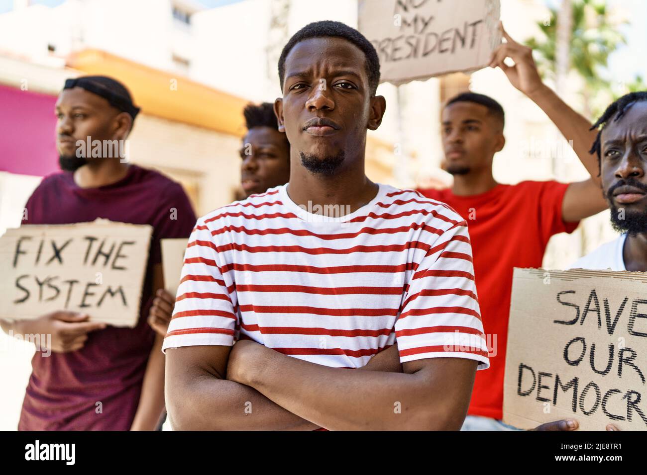 Young activist man with arms crossed gesture standing with a group of ...
