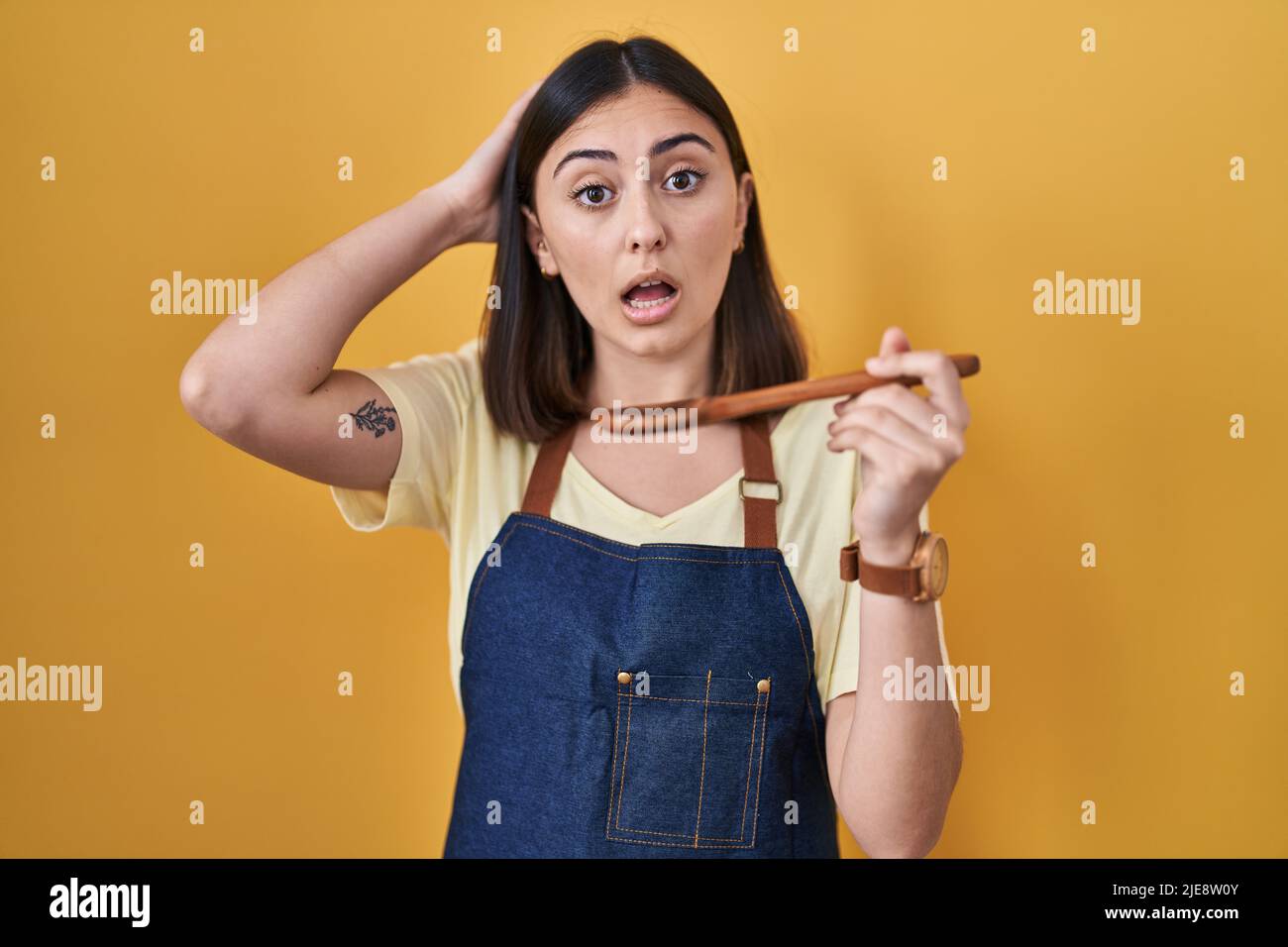 Hispanic girl eating healthy wooden spoon crazy and scared with hands ...