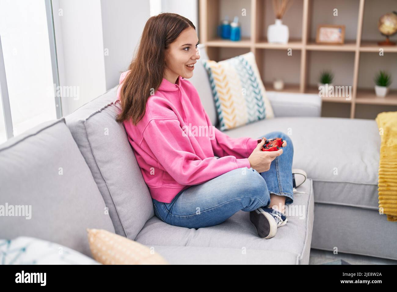 Young woman playing video game sitting on sofa at home Stock Photo - Alamy