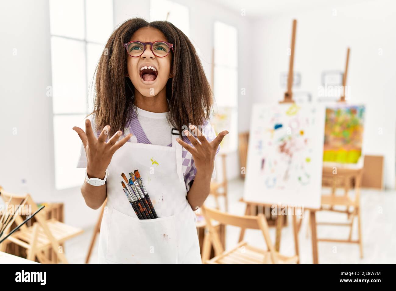 Young african american girl painting at art studio crazy and mad ...