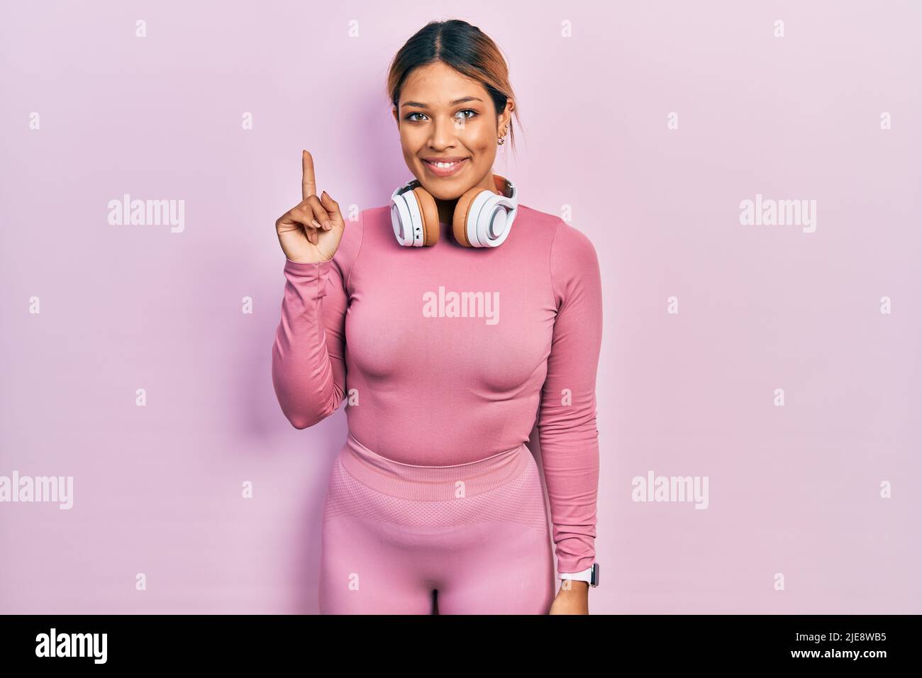 Beautiful hispanic woman wearing gym clothes and using headphones ...