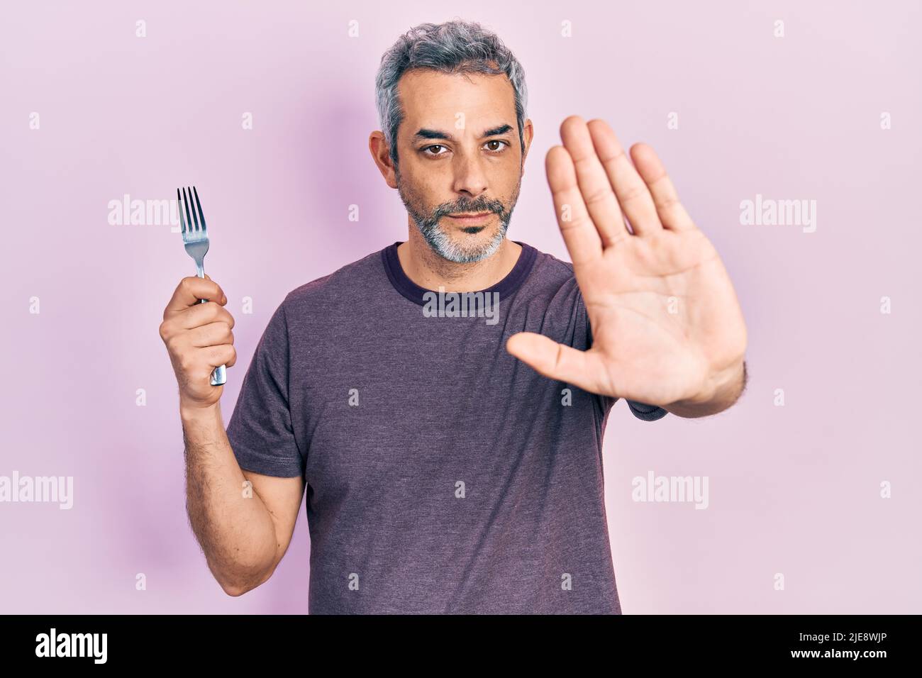 Handsome middle age man with grey hair holding one silver fork with ...