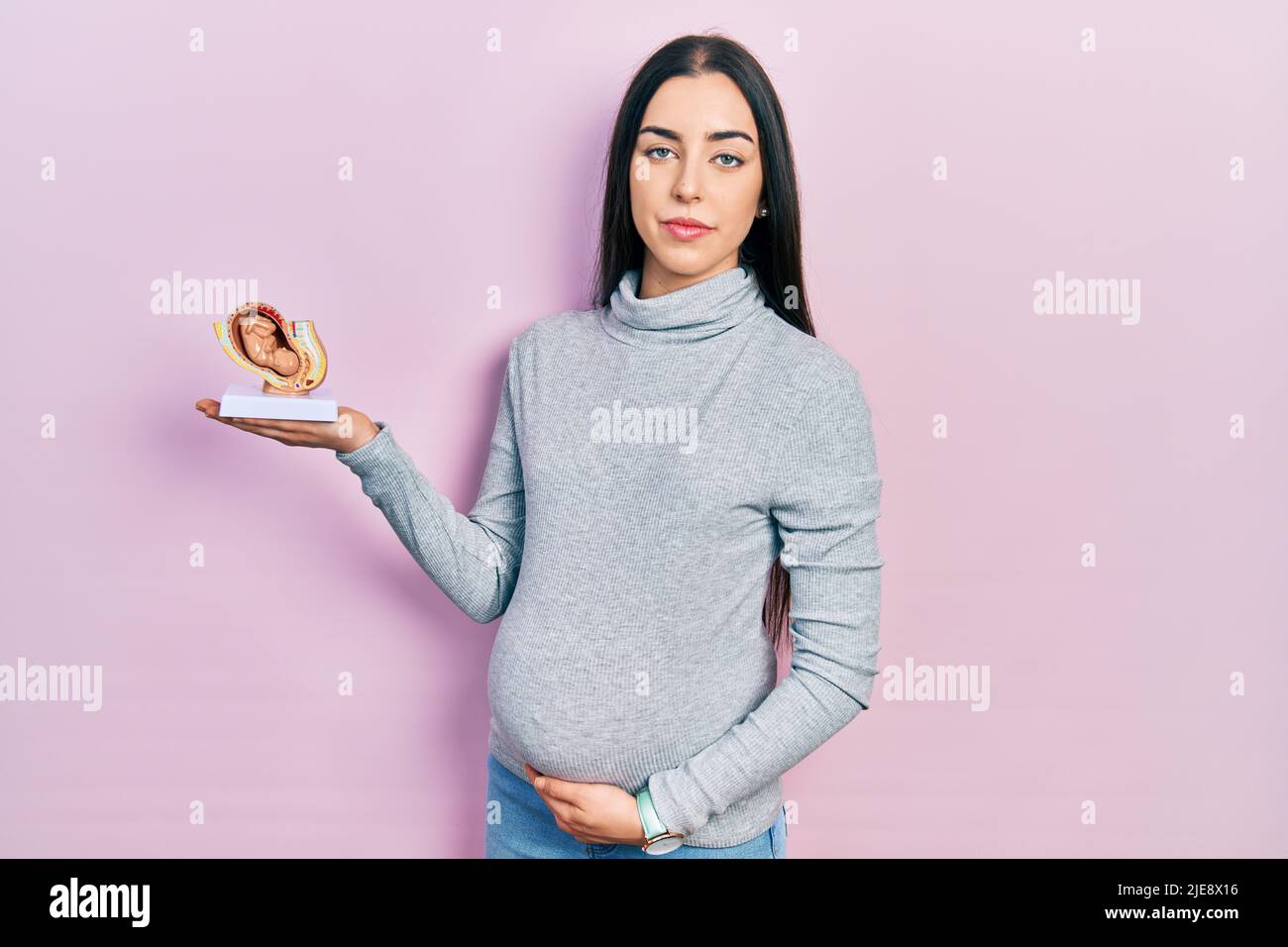 Beautiful woman with blue eyes expecting a baby, holding anatomic fetus ...