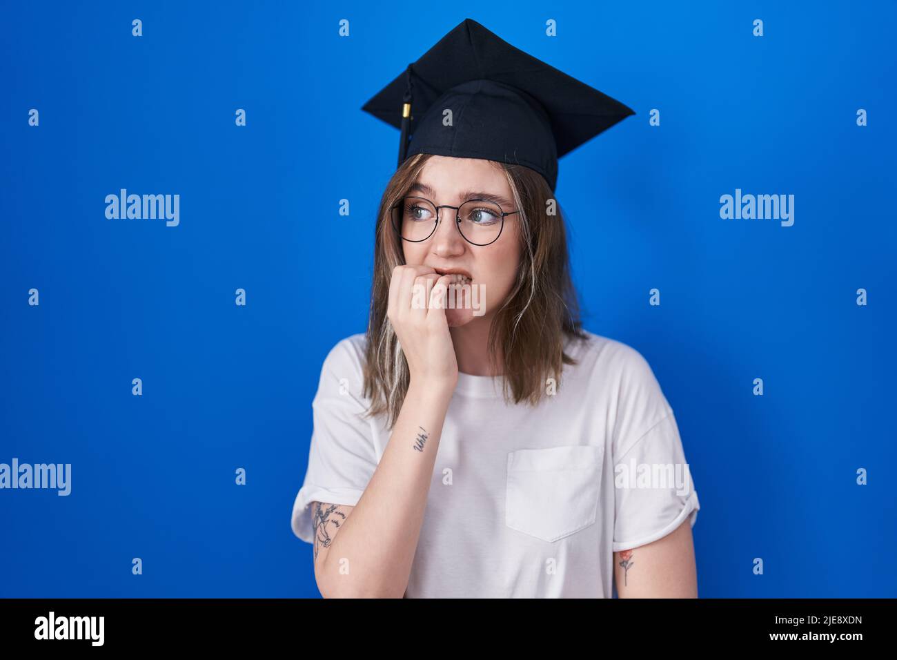 Blonde caucasian woman wearing graduation cap looking stressed and ...