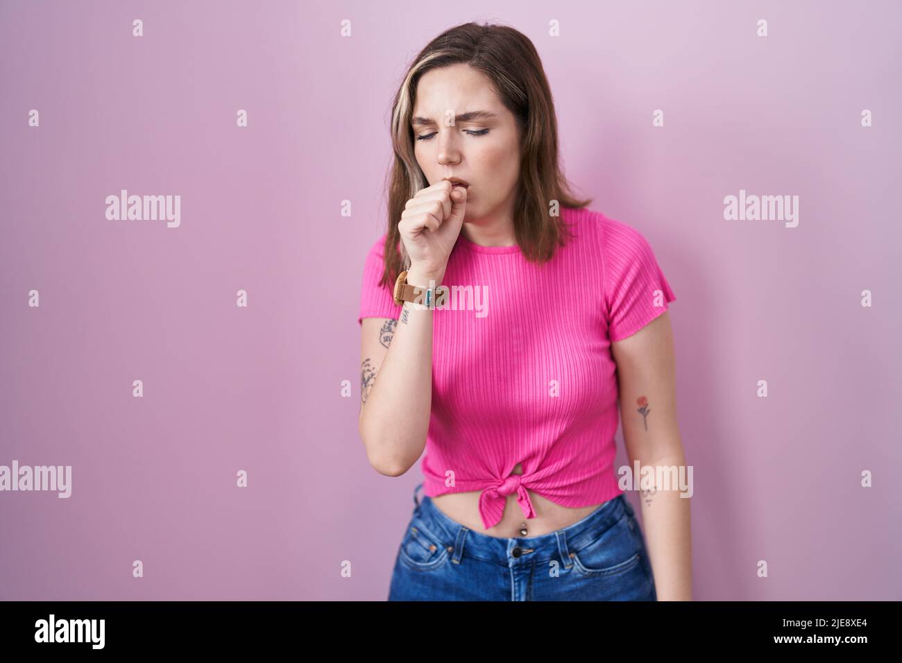 Blonde caucasian woman standing over pink background feeling unwell and ...