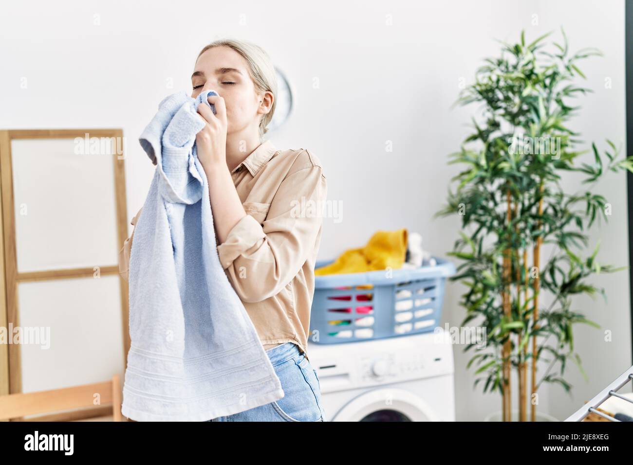 Young caucasian woman smiling confident smelling clothes at laundry ...