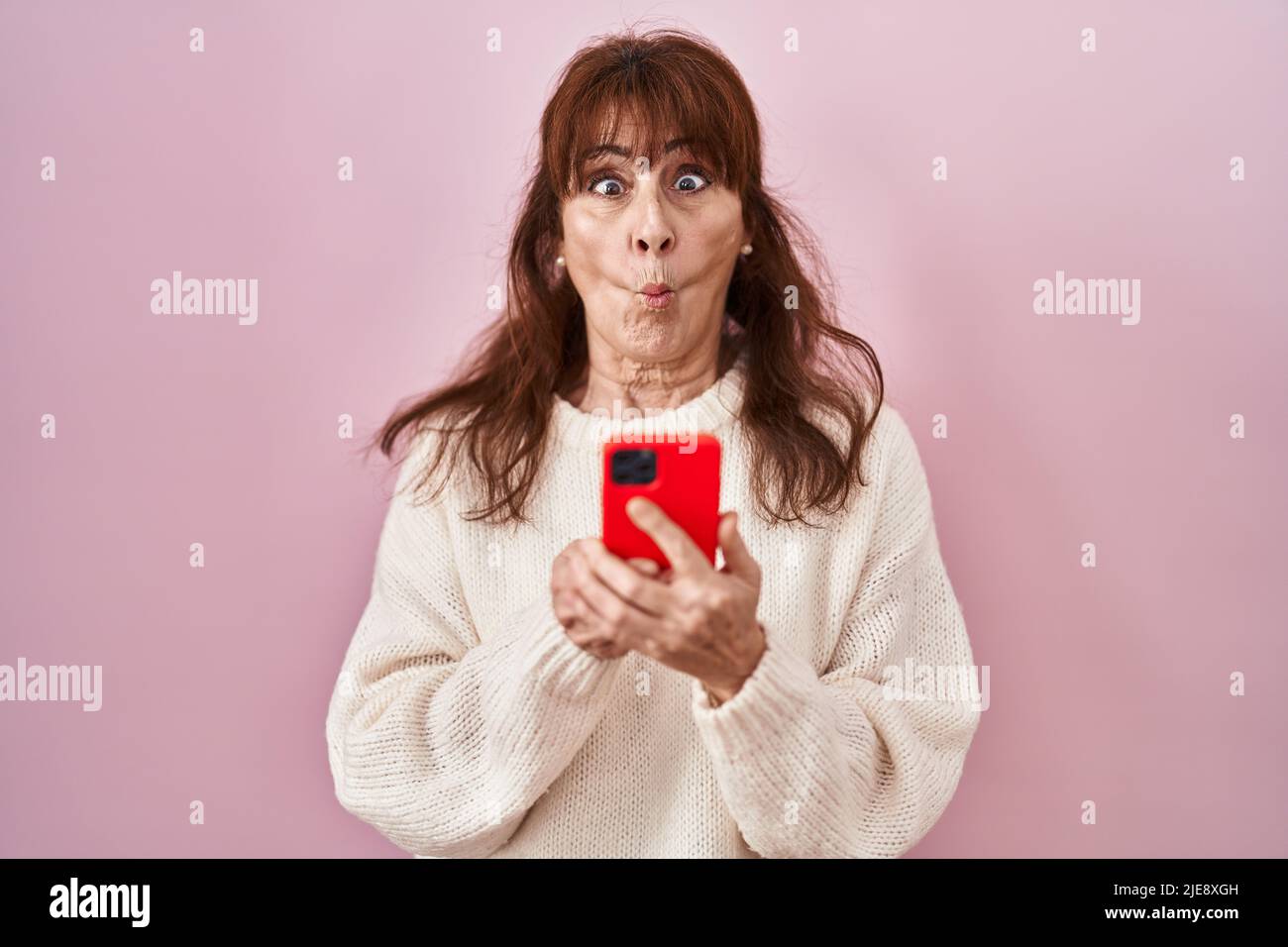 Middle age hispanic woman using smartphone typing message making fish ...