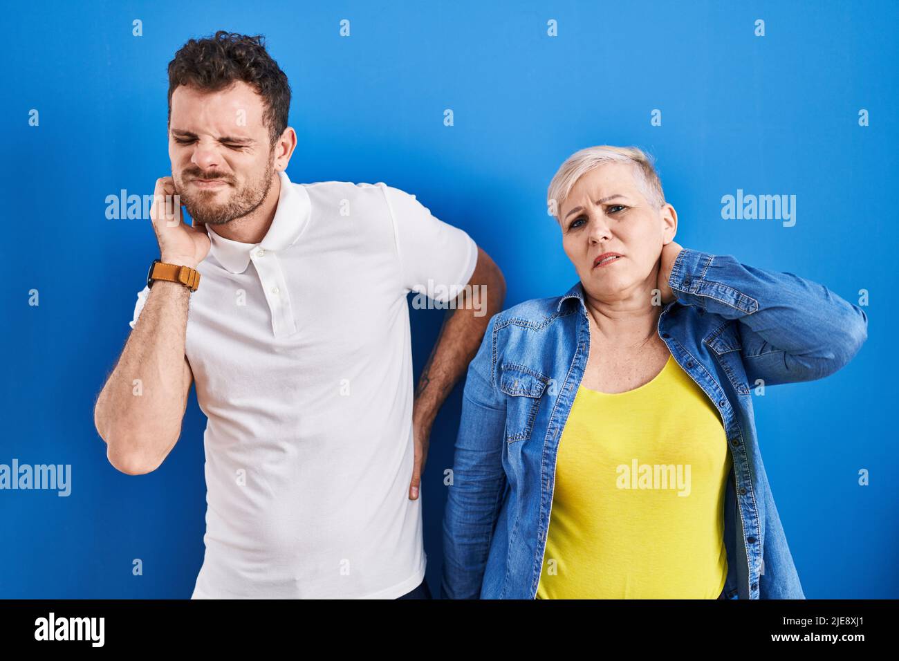 Young brazilian mother and son standing over blue background suffering ...