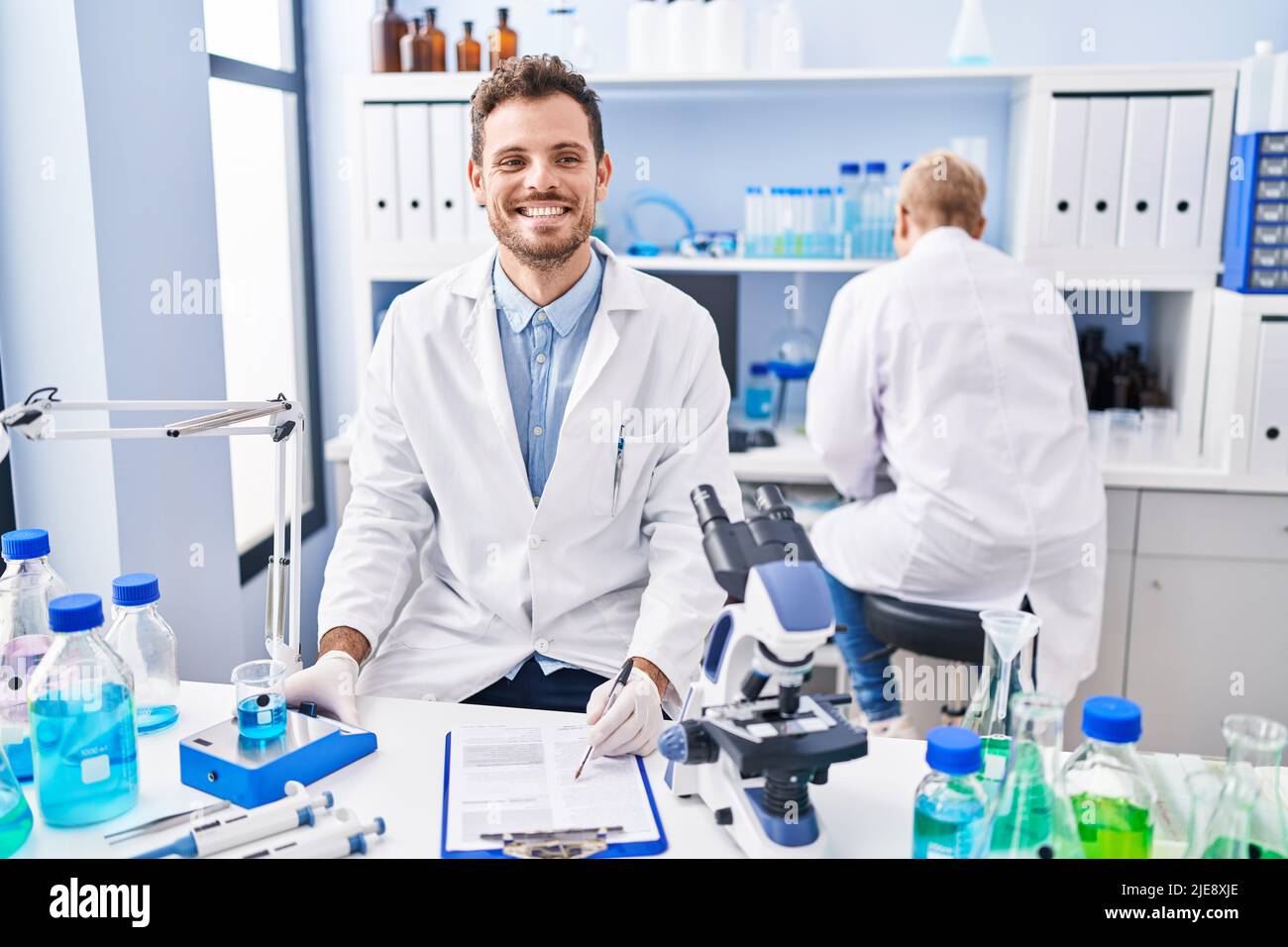 Hispanic man and woman working at scientist laboratory looking positive ...