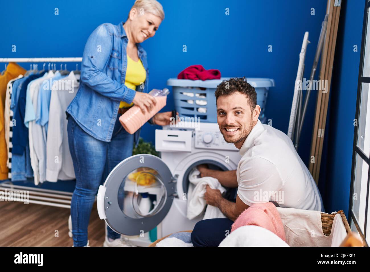 Mother and son washing clothes pouring detergent on washing machine at ...