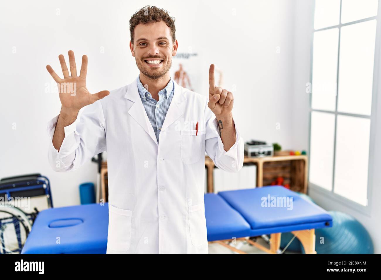 Handsome young man working at pain recovery clinic showing and pointing ...