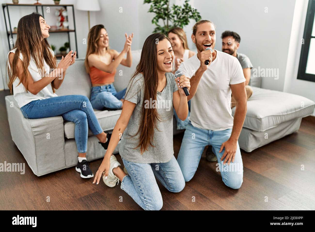 Group of young friends having party singing song using microphone at ...