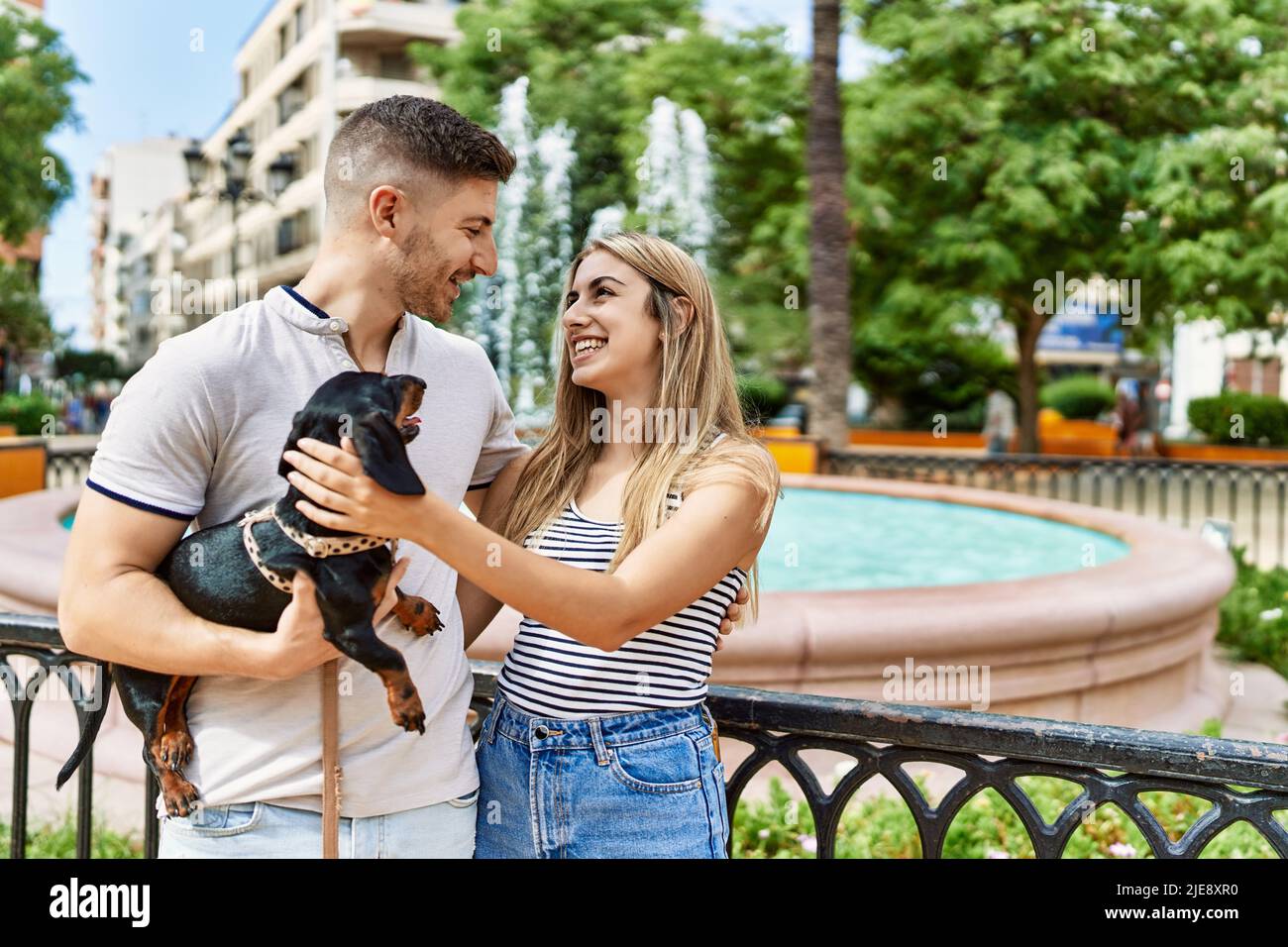 Young caucasian couple hugging and smiling happy standing with dog at ...