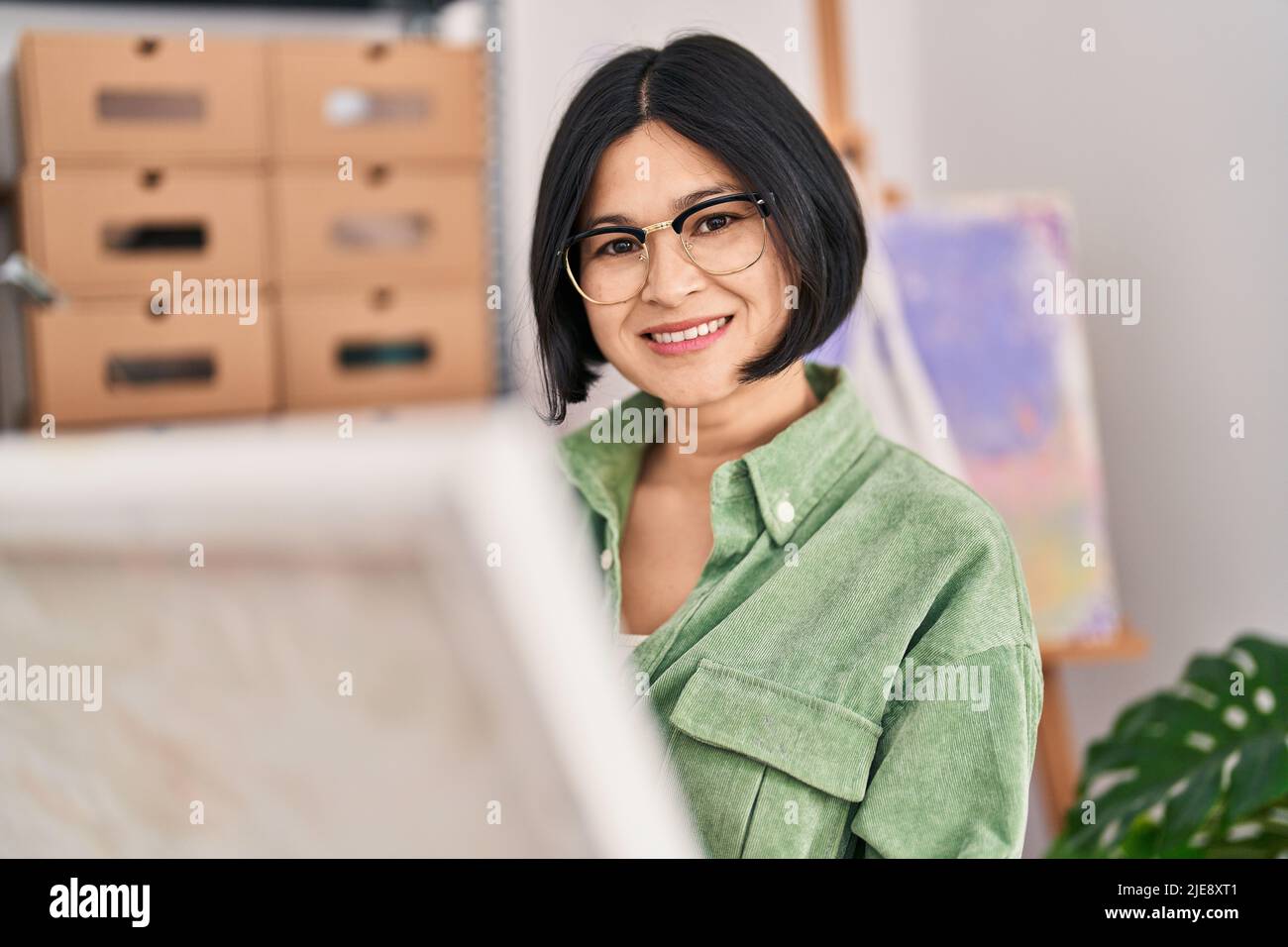 Young chinese woman artist smiling confident looking draw at art studio ...