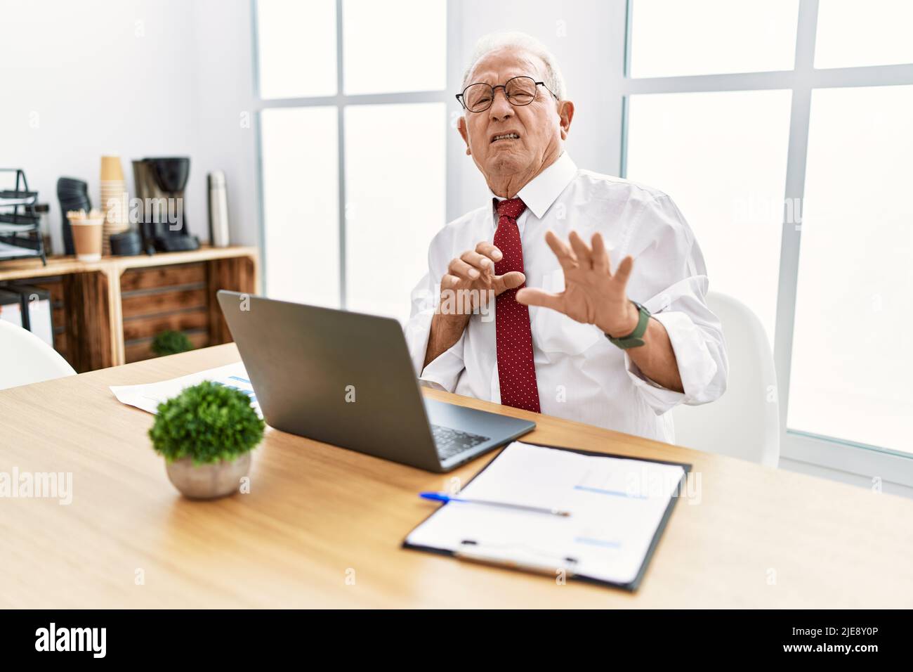 Senior man working at the office using computer laptop disgusted ...