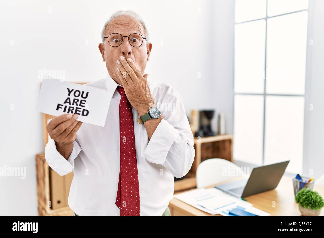 Senior business man holding you are fired banner at the office covering ...