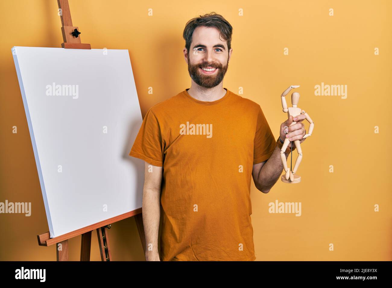Caucasian man with beard standing by painter easel stand holding ...