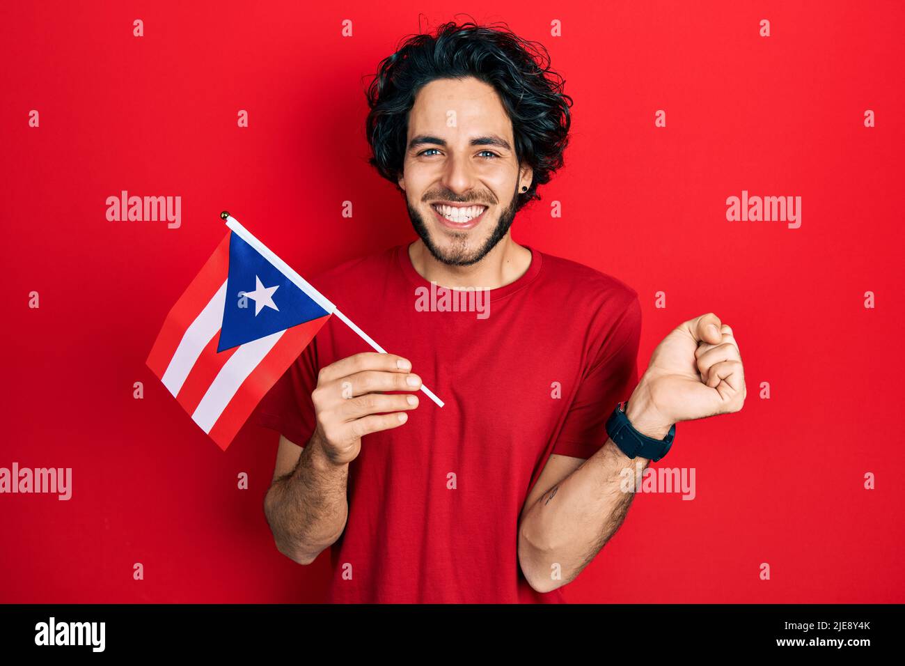 Handsome hispanic man holding puerto rico flag screaming proud ...