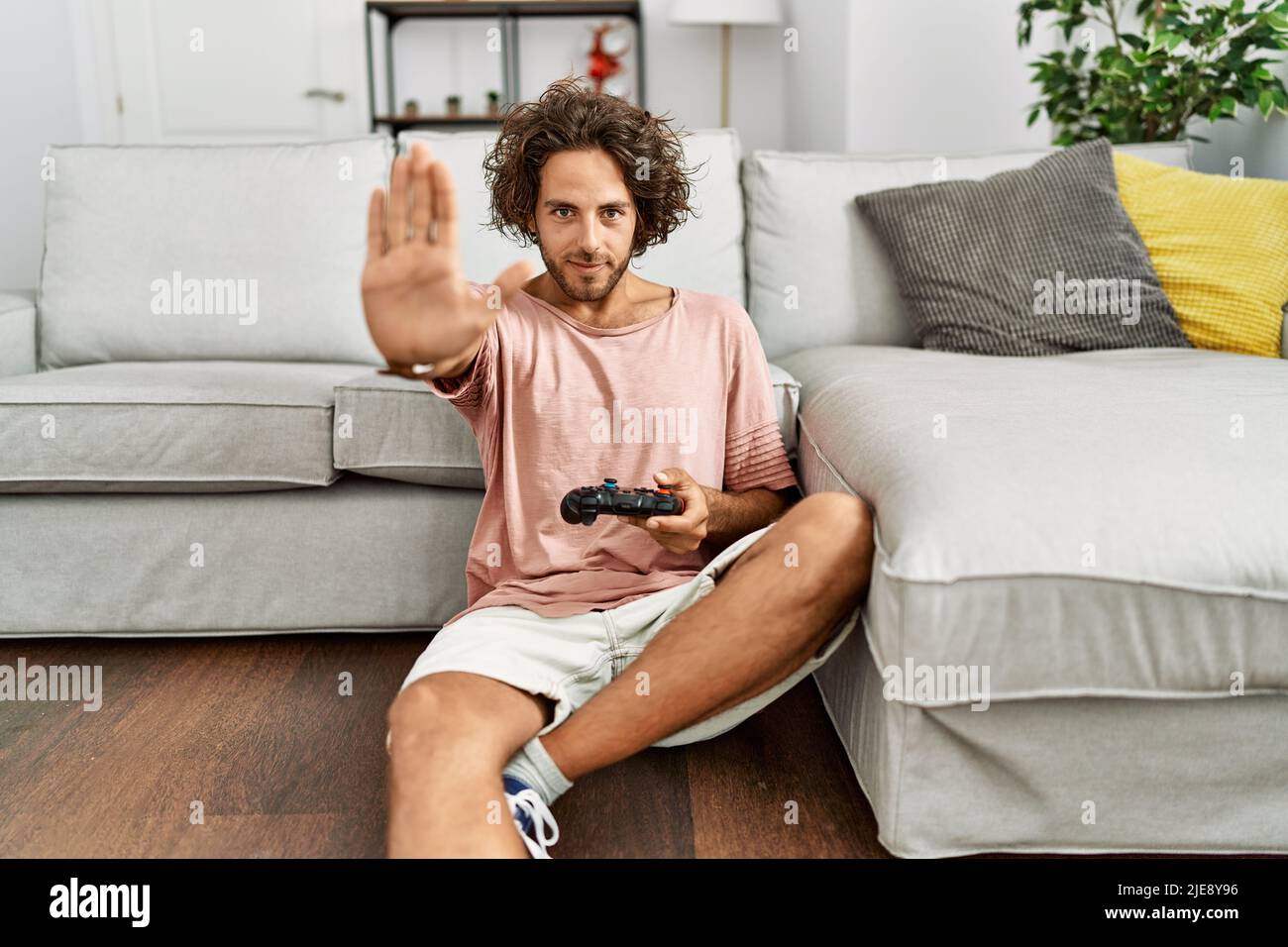 Young hispanic man playing video game holding controller at home with ...