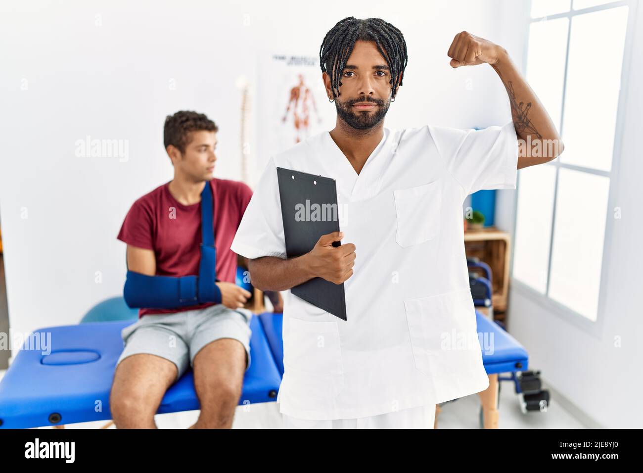 Young hispanic man working at pain recovery clinic with a man with ...