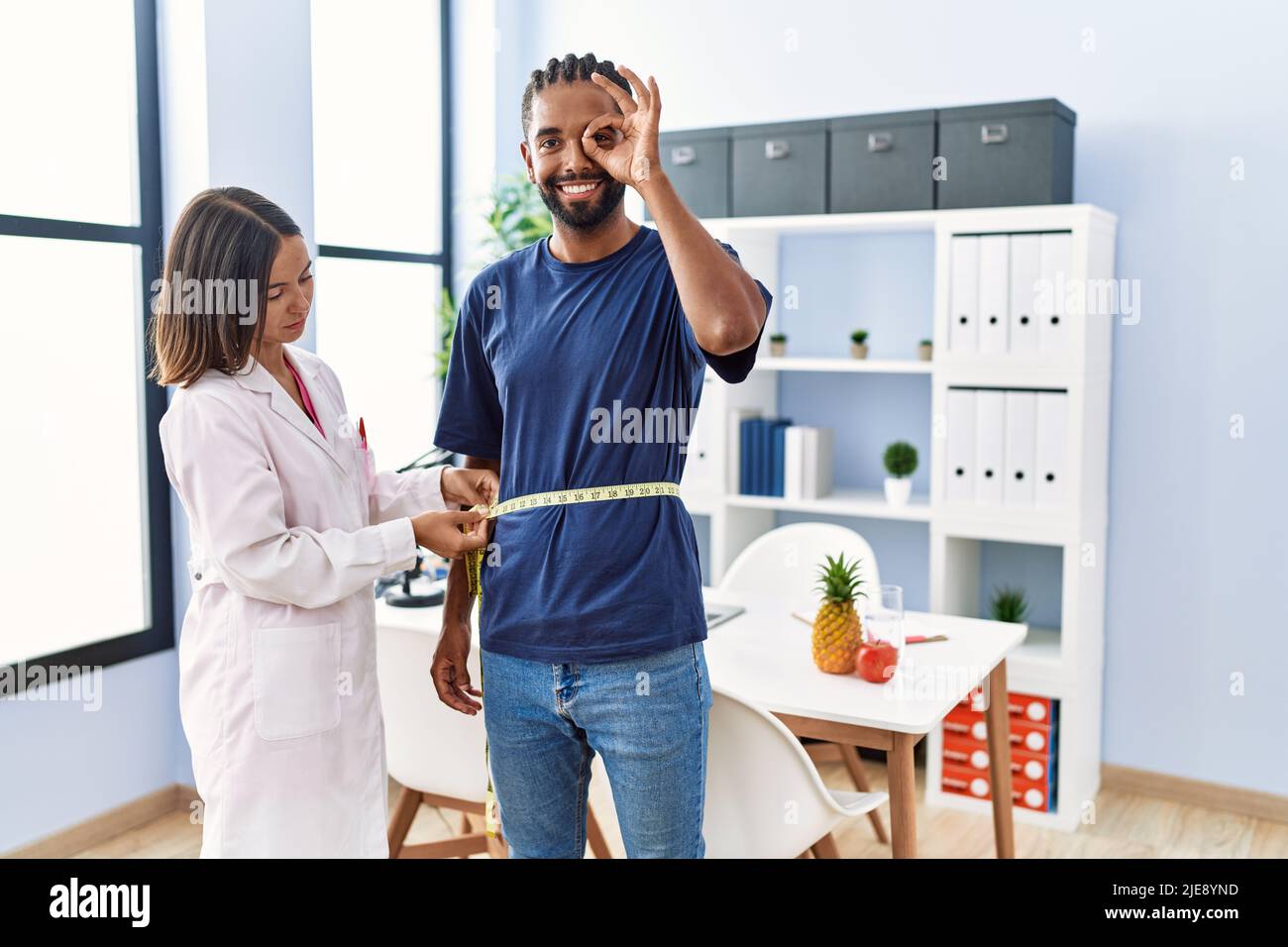 Dietitian at the clinic using tape measure measuring waist of client ...