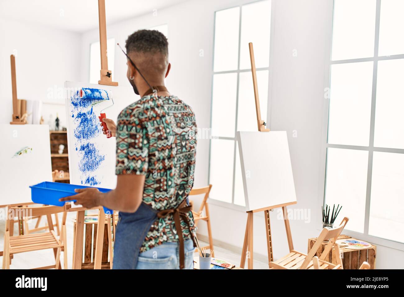 Young african american artist man on back view painting with paint ...