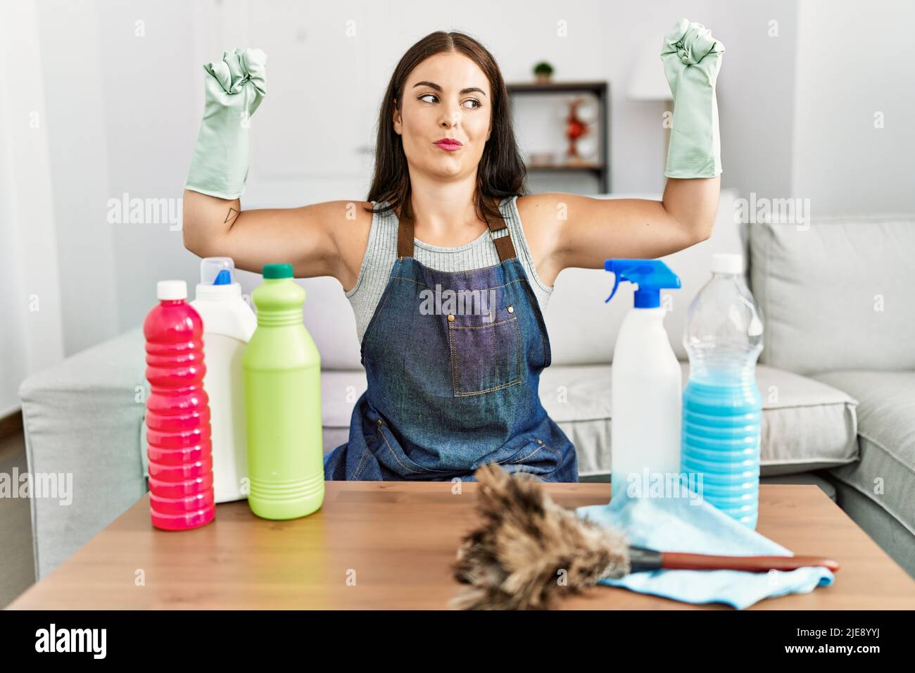 Young brunette woman wearing cleaner apron and gloves cleaning at home ...