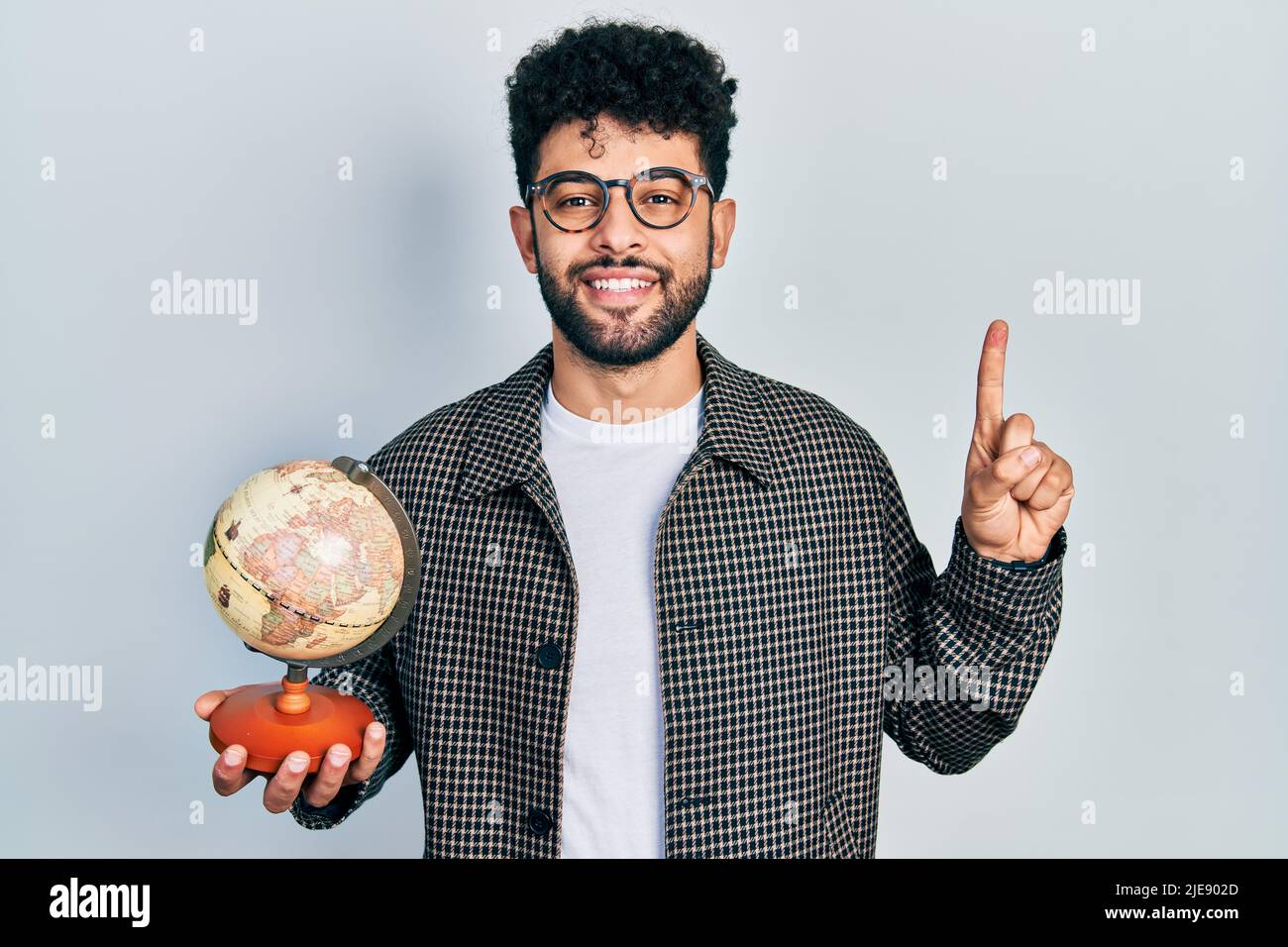Young arab man with beard holding vintage world ball smiling with an ...