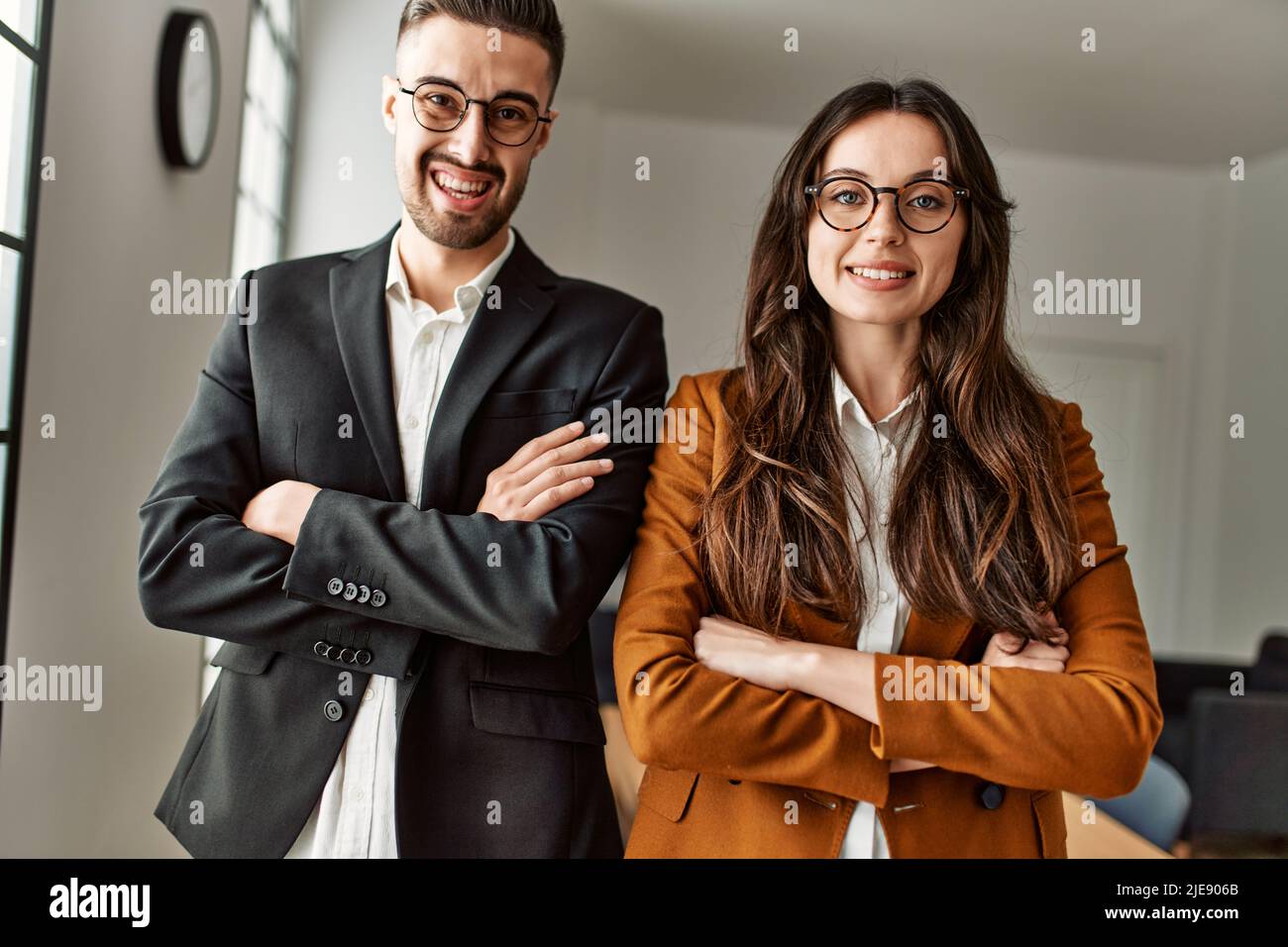 Two business workers smiling happy standing with arms crossed gesture ...
