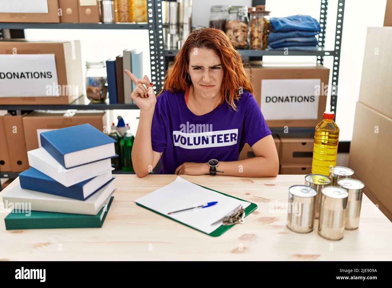 Young redhead woman wearing volunteer t shirt at donations stand ...