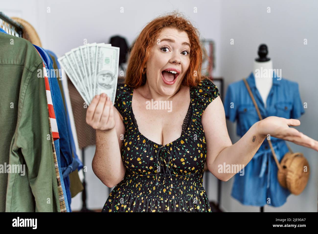 Young redhead woman holding shopping bags and dollars celebrating ...