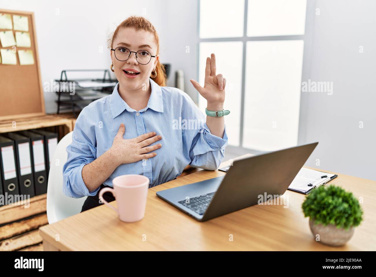 Young redhead woman working at the office using computer laptop smiling ...