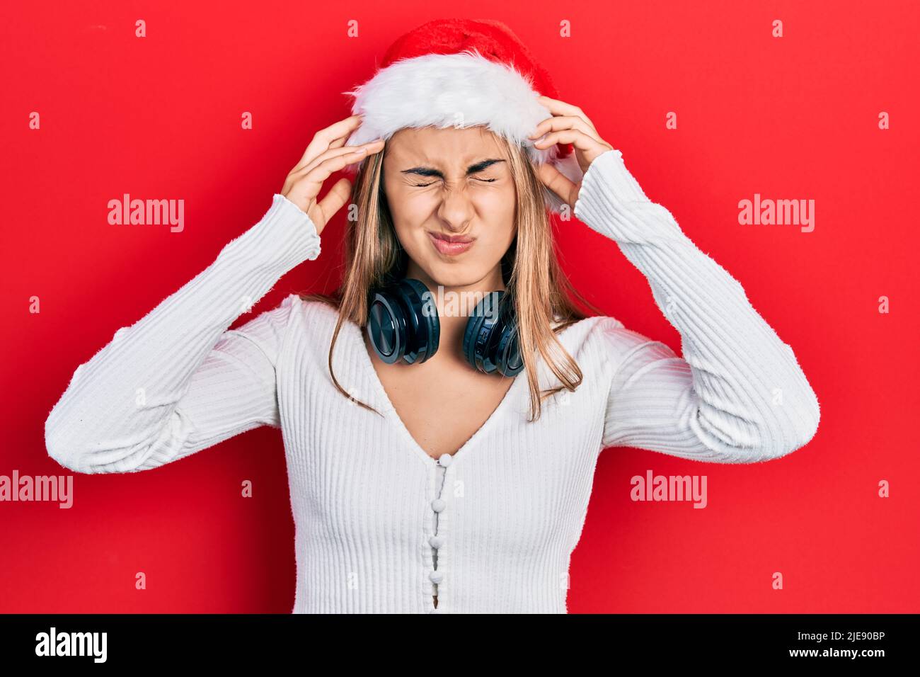 Beautiful hispanic woman wearing christmas hat and headphones with hand ...