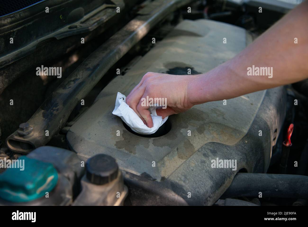 Man's hand unscrews the cap of the oil filler neck of the engine ...