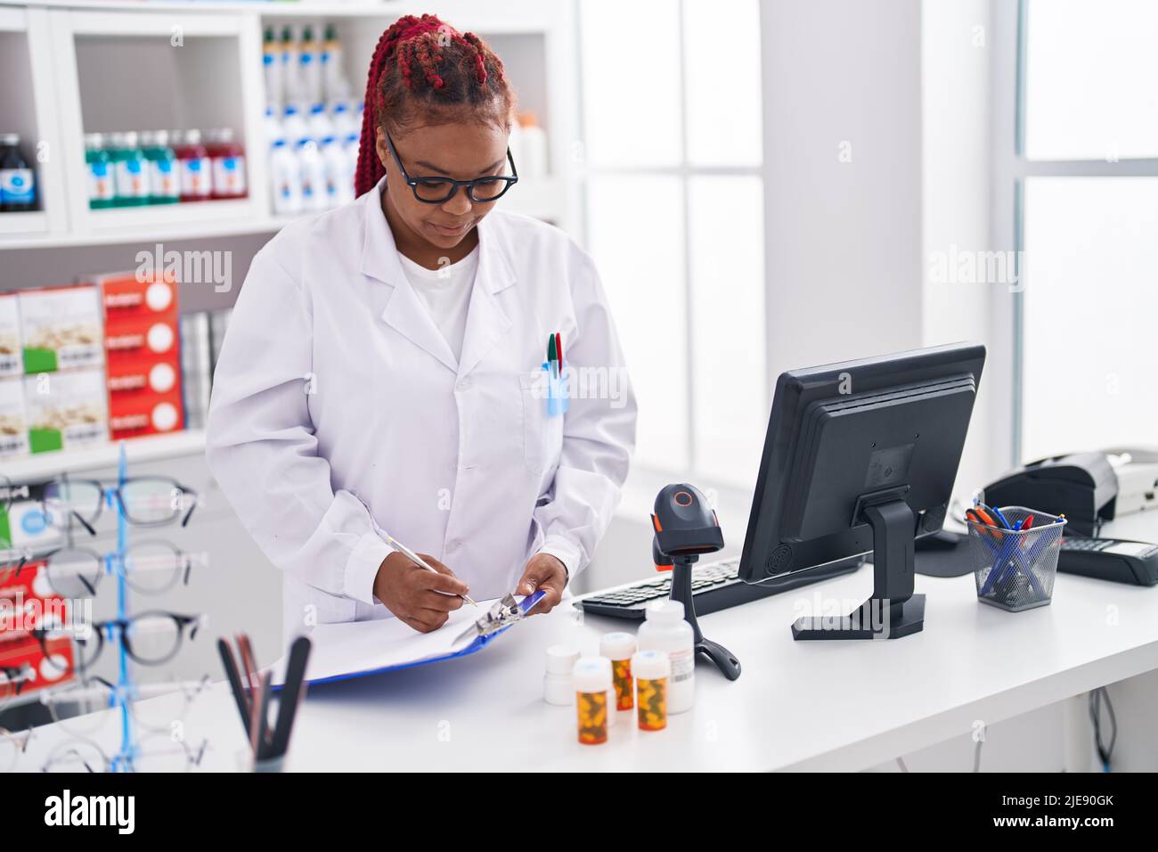 African american woman pharmacist writing on checklist at pharmacy ...