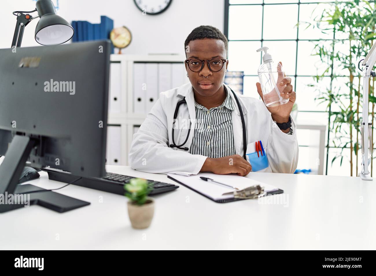 Young african doctor man holding hand sanitizer gel at the clinic ...