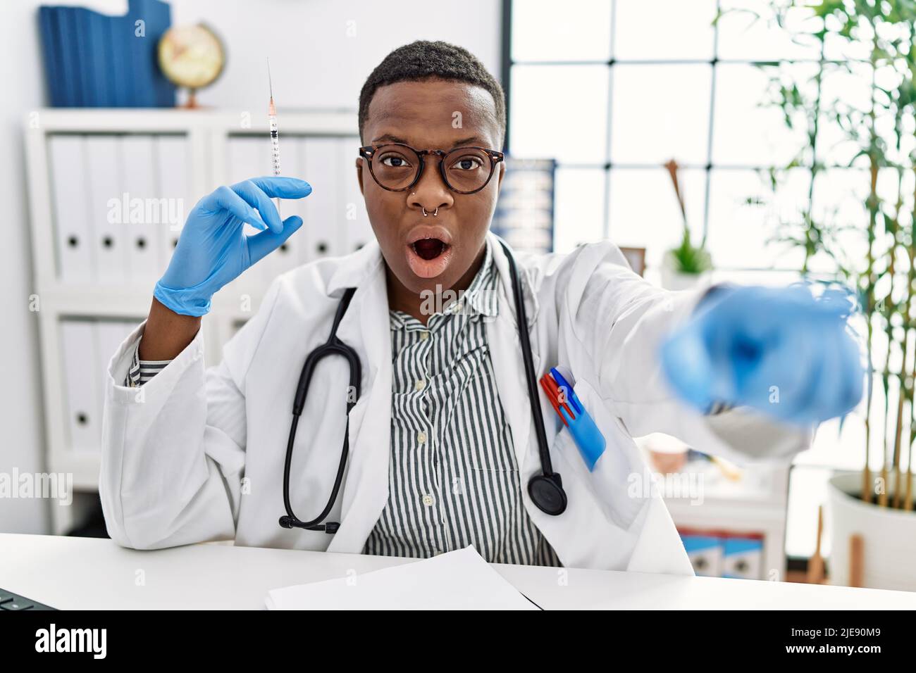 Young african doctor man holding syringe at the hospital pointing with ...
