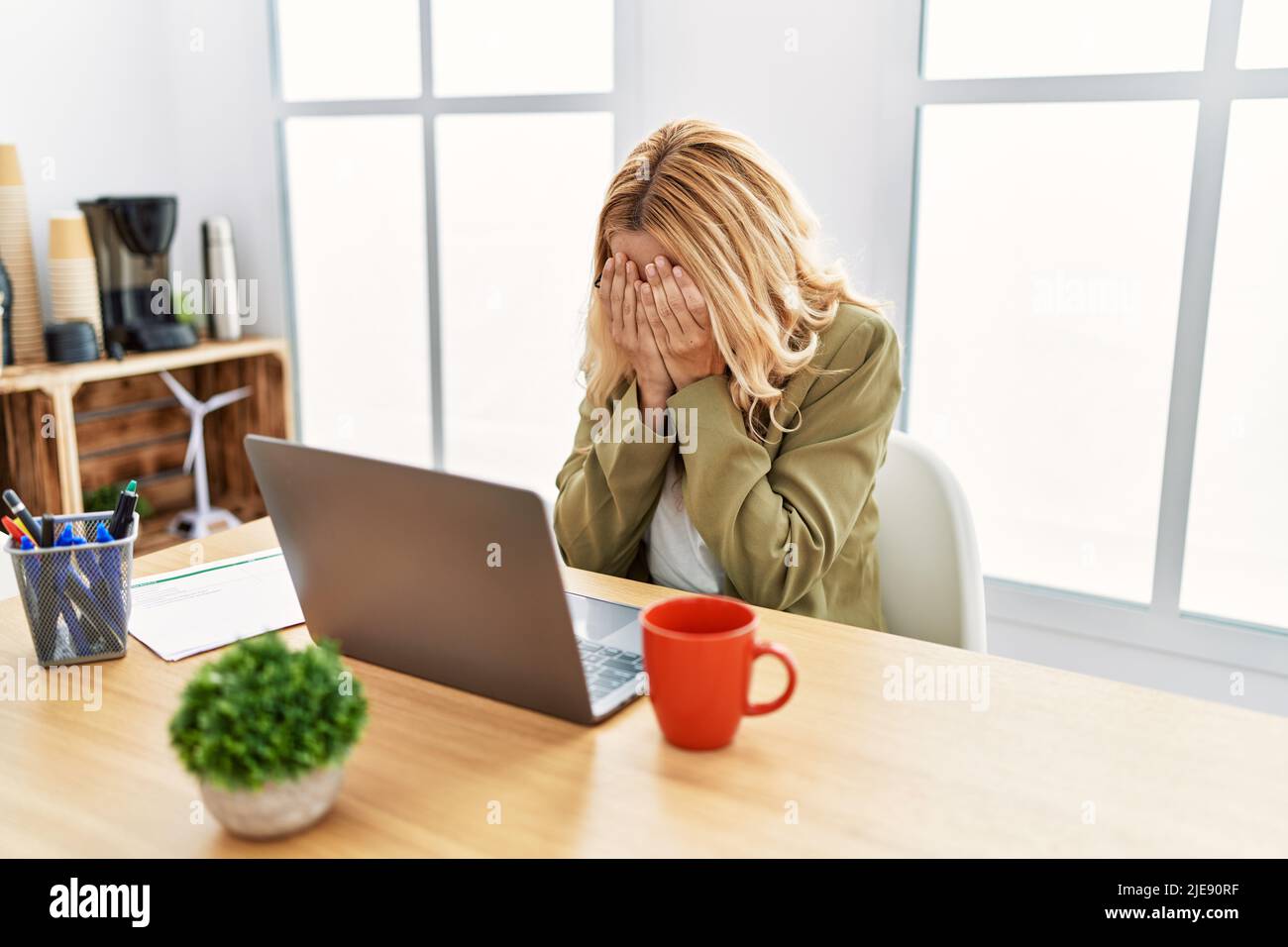 Beautiful blonde woman working at the office with laptop with sad ...