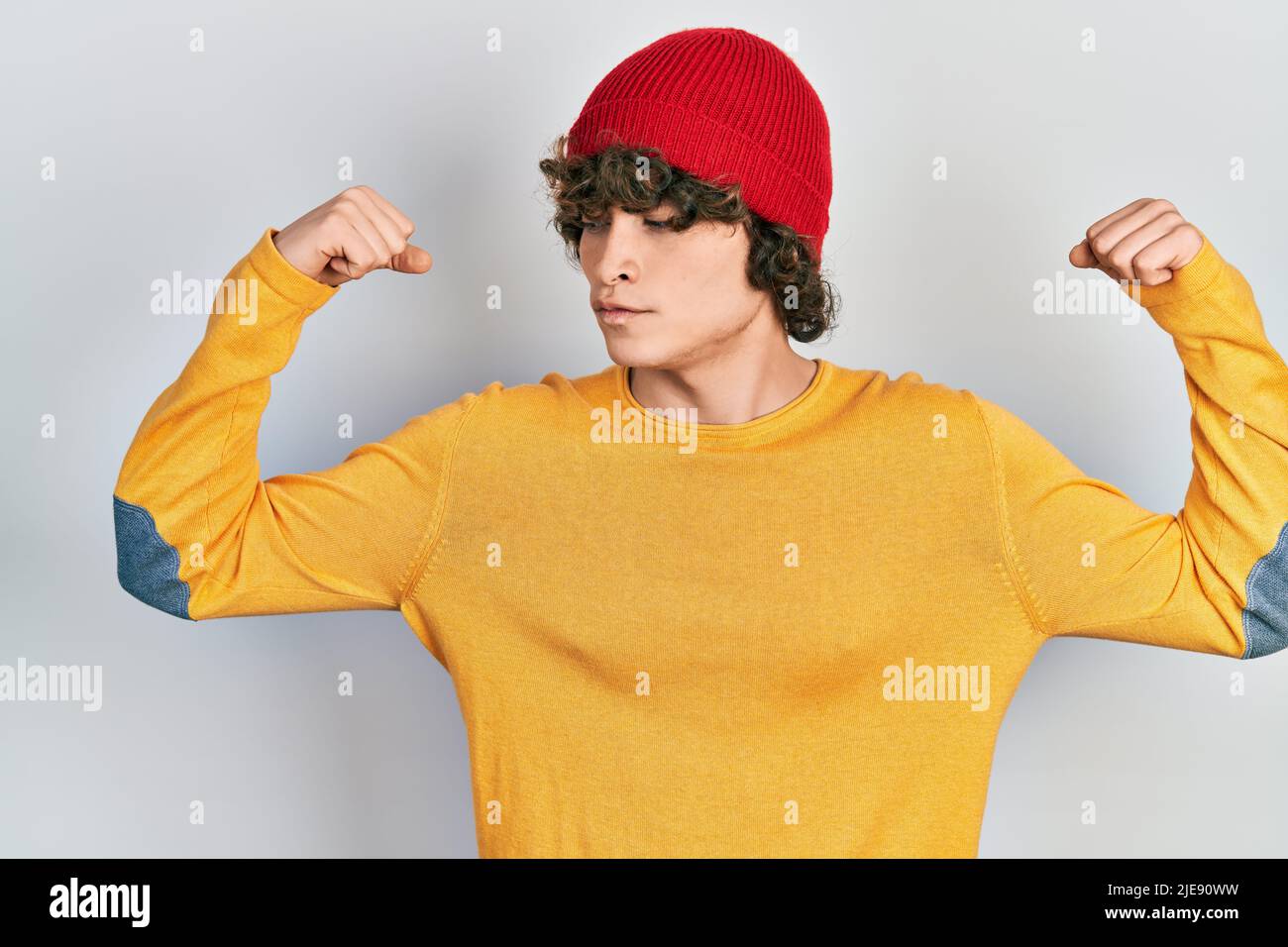 Handsome young man wearing wool hat showing arms muscles smiling proud ...