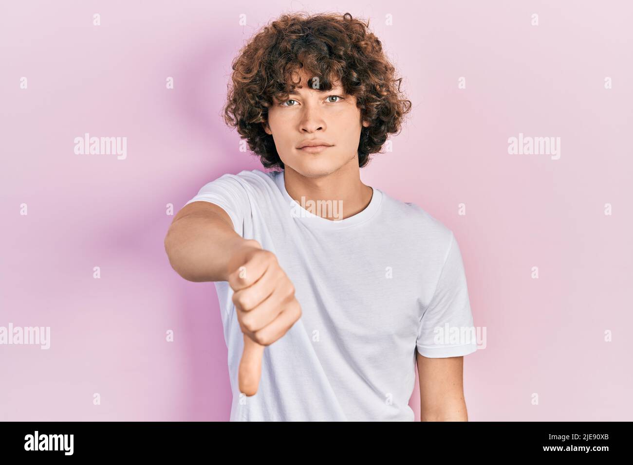 Handsome young man wearing casual white t shirt looking unhappy and ...