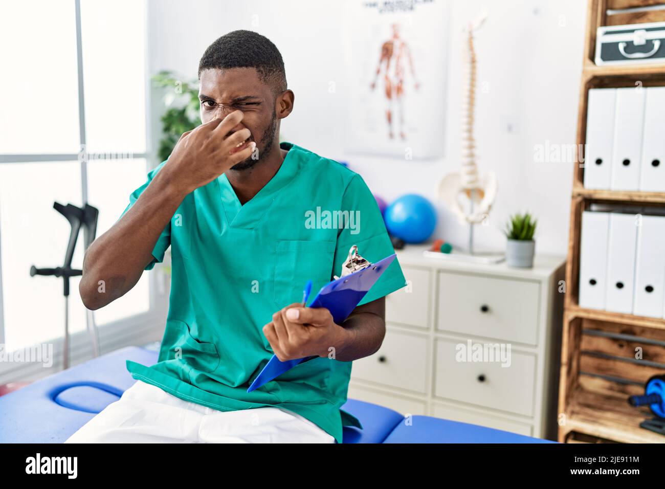 Young african american man working at pain recovery clinic smelling ...