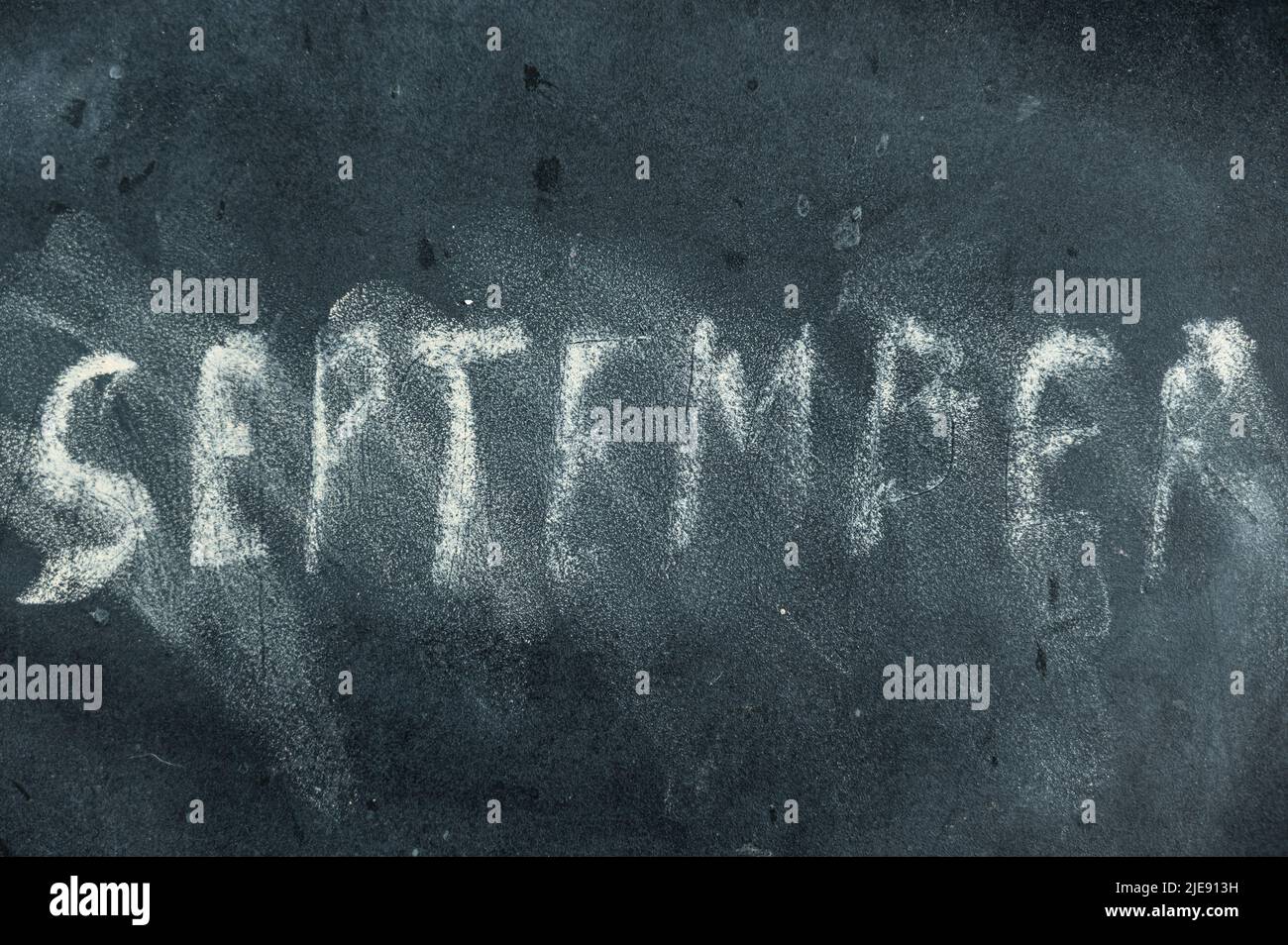 Semi-erased word SEPTEMBER on black chalkboard. Handwritten word. Fuzzy ...