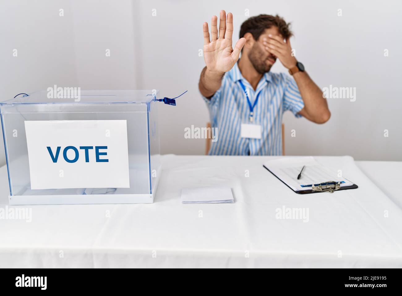 Young handsome man at political election sitting by ballot covering ...