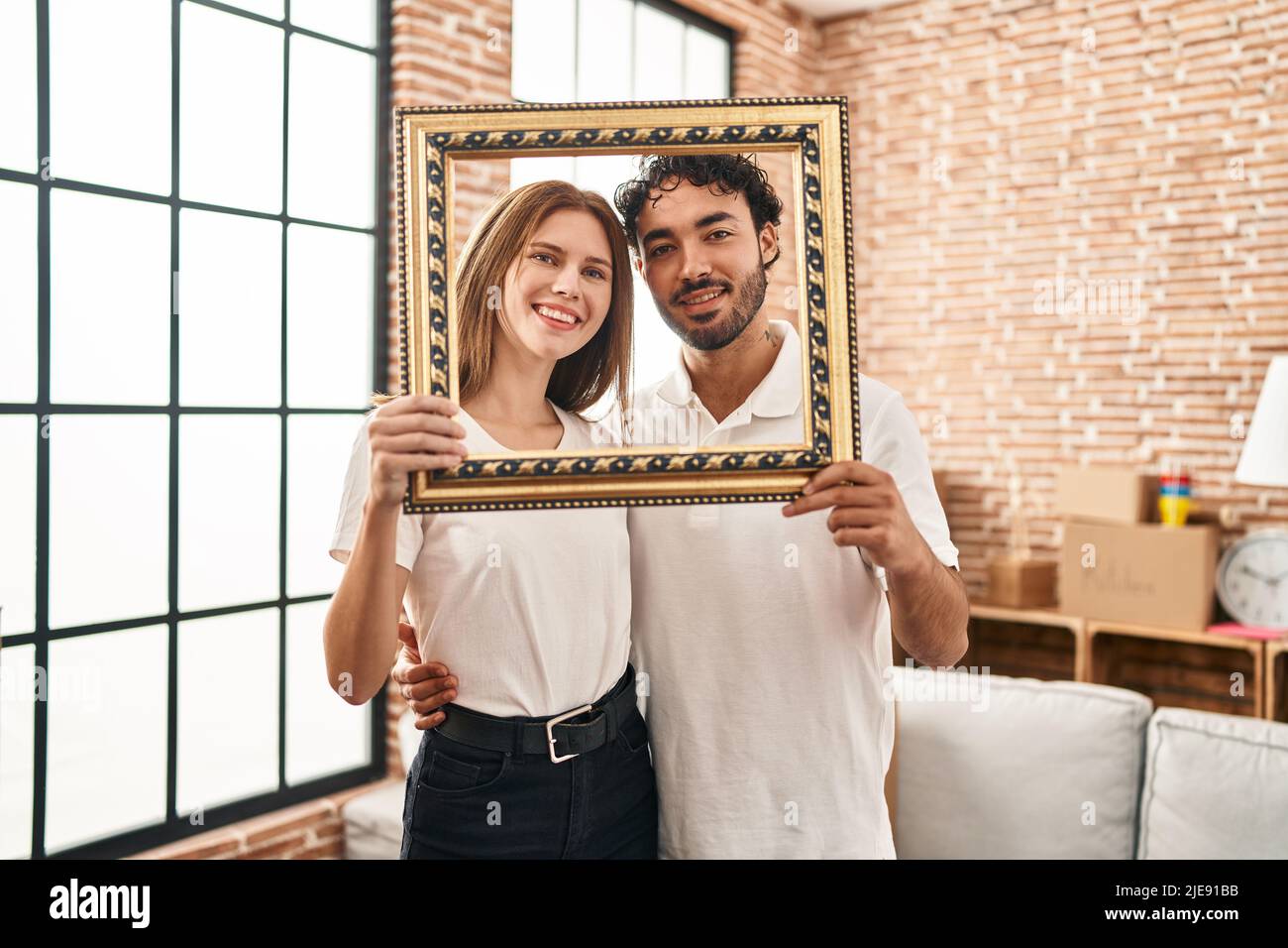 Young two people holding empty frame together smiling with a happy and ...