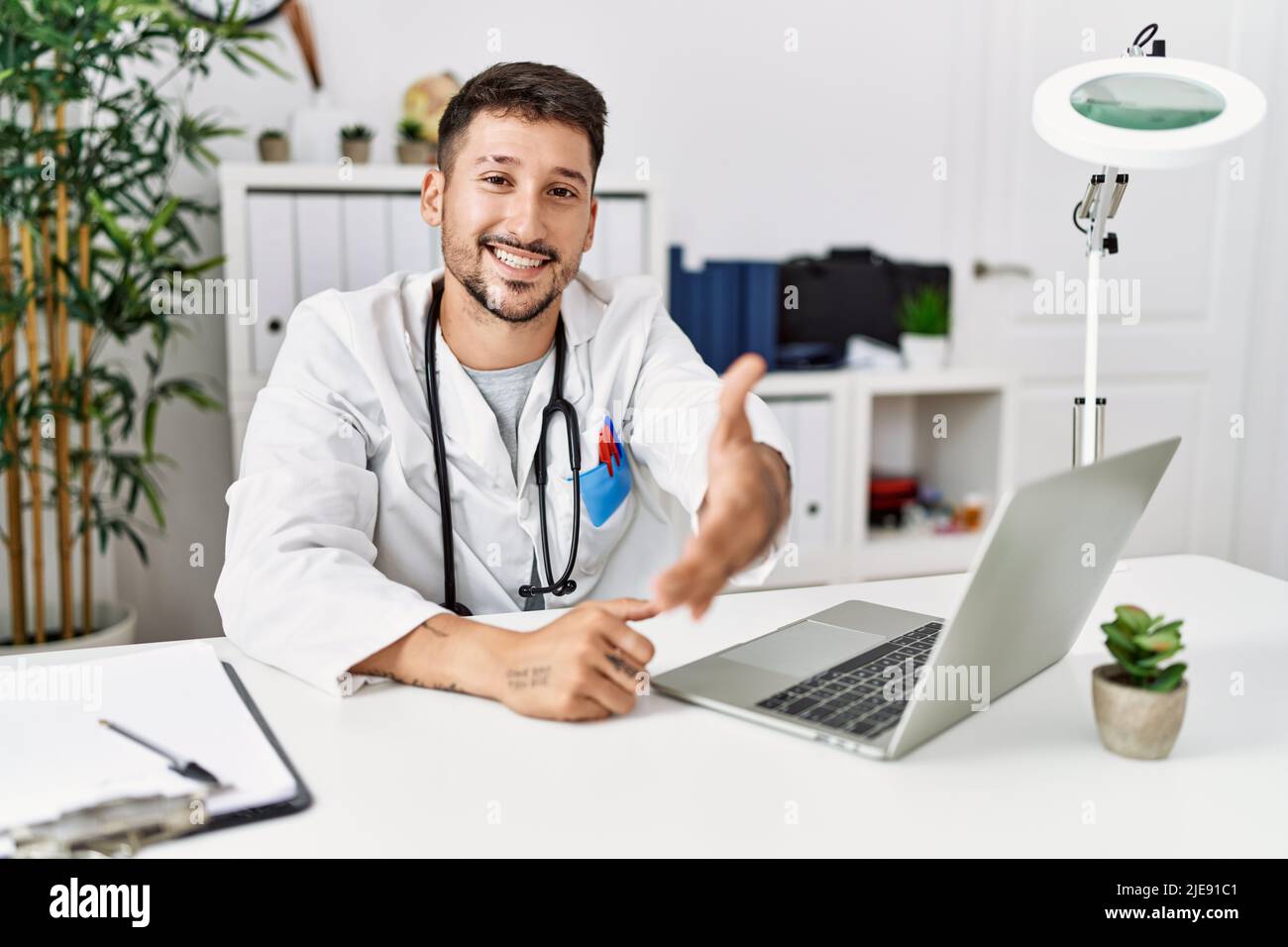 Young doctor working at the clinic using computer laptop smiling ...